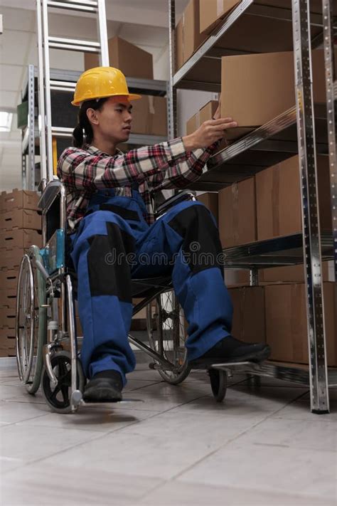 Young Asian Warehouse Worker Using Wheelchair While Doing Inventory