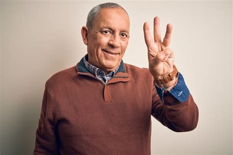 고립 된 흰색 배경 위에 서있는 우아한 스웨터를 입은 선임 잘생긴 남자는 자신감과 행복한 미소를 지으면서 손가락 번호 3을 가리키고 있습니다 남자에 대한 스톡 사진 및 기타