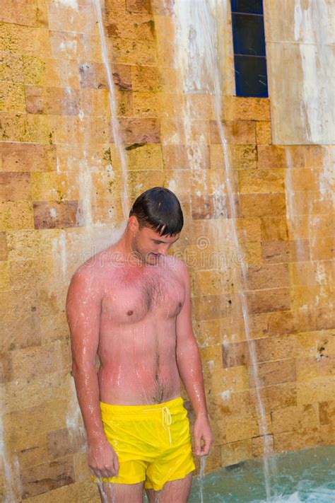 Homem Considerável Novo Que Toma O Chuveiro Exterior Como Uma Cachoeira