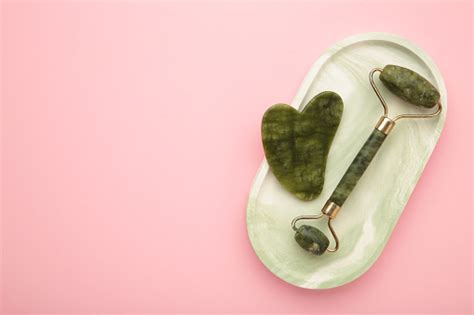 얼굴 마사지 롤러와 구아슈는 분홍색 배경에 석고 쟁반에 있다 자아와 뷰티 케어의 개념 건강관리와 의술에 대한 스톡 사진 및 기타