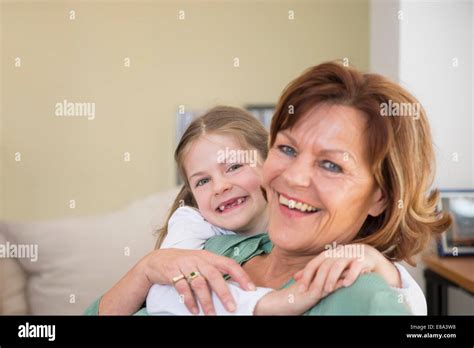 Portrait Of Grandmother And Granddaughter Sitting On Couch In Living