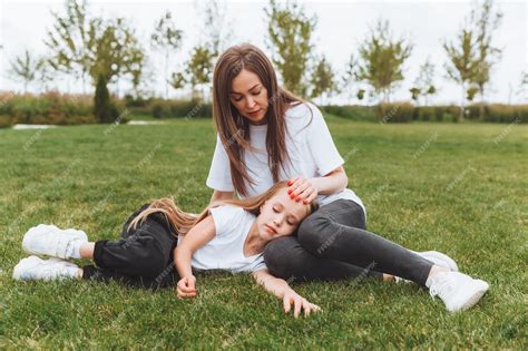 Una Madre Feliz Y Su Hija Están Sentadas En El Césped Del Parque Y