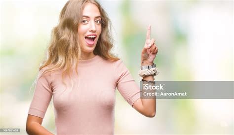 성공적인 아이디어와 손가락 가리키는 격리 된 배경 위에 아름 다운 젊은 금발 여자 종료 하 고 행복 번호 하나입니다 가리키기에