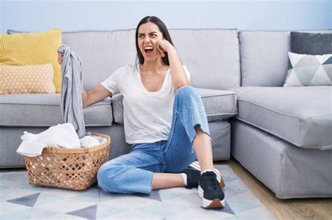 Young Brunette Woman Doing Laundry At Home Angry And Mad Screaming
