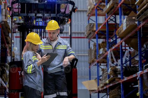 Two Male And Female Factory Checkers Are Discussing Work On A Warehouse