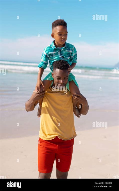 African American Young Father Carrying Son On Shoulders While Standing