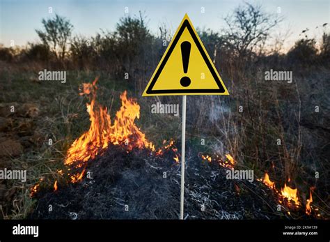 Burning Dry Grass And Warning Sign With Exclamation Mark Warns About