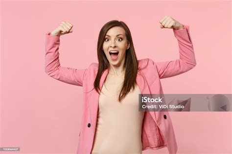 자 켓에 강한 쾌활 한 젊은 여자의 초상화 팔 뚝을 보여주는 입을 열어 파스텔 핑크 벽 배경에 고립 된 근육 사람들은 진심으로
