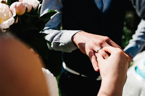 모란의 꽃다발을 가진 세련 된 신부는 신랑의 손가락 손에 금 반지를 착용 자연의 배경에 결혼식 아침 닫습니다 2명에 대한 스톡