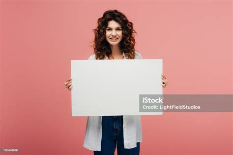 분홍색에 서 있는 동안 빈 현수막을 들고 행복 한 젊은 여자 곱슬 머리에 대한 스톡 사진 및 기타 이미지 곱슬 머리 명랑한