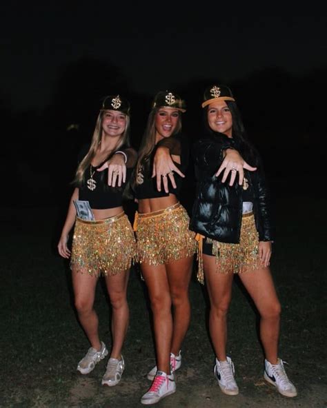 Three Young Women Dressed In Gold Sequins Posing For The Camera At An