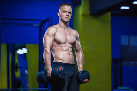 Estúdio Disparado De Um Modelo Masculino Que Guarda Pesos Em Ambas As