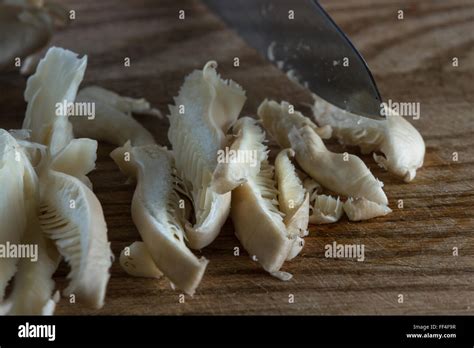 Close Up Of A Chefs Hands Slicing Raw Mushrooms On A Wooden Cutting