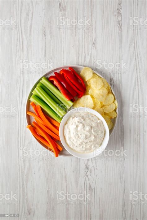 감자 칩 셀러리 후추 당근을 곁들인 수제 캐러멜화된 양파 딥을 흰색 나무 배경에 얹어 최고경관을 감상할 수 있습니다 평면 누워