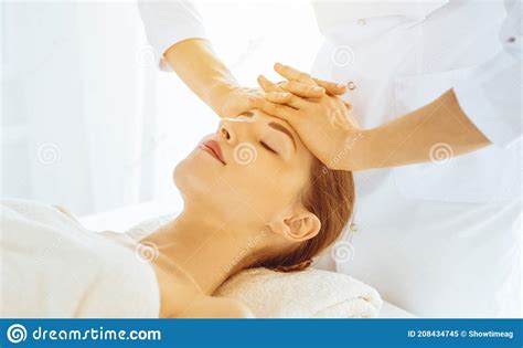 Beautiful Woman Enjoying Facial Massage With Closed Eyes In Sunny Spa