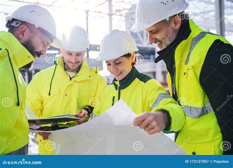 A Group Of Engineers Standing On Construction Site Working Stock