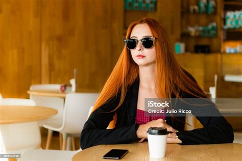 카페테리아에서 선글라스와 함께 아름 다운 빨간 머리 모델입니다 배경 흐리게 테이블에 핸드폰과 커피 컵 20 29세에 대한 스톡