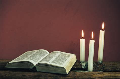 아름다운 오픈 성경과 오래된 오크 나무 테이블과 붉은 벽 배경에 세 개의 흰색 연소 촛불 교회에 대한 스톡 사진 및 기타 이미지