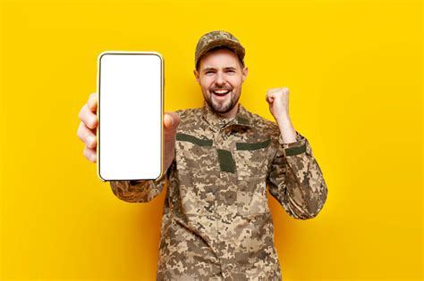 군용 위장 제복 픽셀을 입은 우크라이나 육군 병사가 스마트폰 화면을 보여주고 노란색 고립된 배경에서 승리를 축하합니다 20 24세에 대한 스톡 사진 및 기타 이미지 Istock