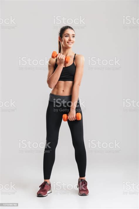 회색 배경에 고립 된 작은 아령과 체육관에서 훈련 스포티 한 슬림 여성의 전체 길이 사진 강사에 대한 스톡 사진 및 기타 이미지