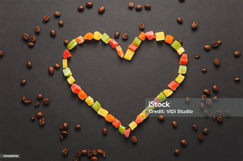 디자인에 대 한 검은 배경에 고립 된 갈색 커피와 심장의 형태에서 다채로운 설탕 졸 임된 과일 Fabruary 14 휴일 개념에