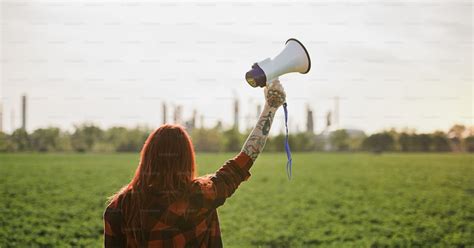 확성기를 든 젊은 여성 활동가가 정유 공장 옆에 서서 항의하는 뒷모습 사진 Unsplash의 성인 이미지