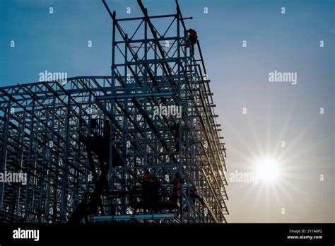 Workers Working At Height On Clad Rack Structure Installing Steel Elements Of Framework During
