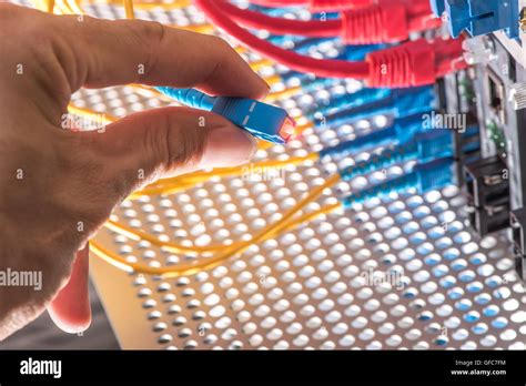 Man Working In Network Server Room With Fiber Optic Hub For Digital Communications And Internet