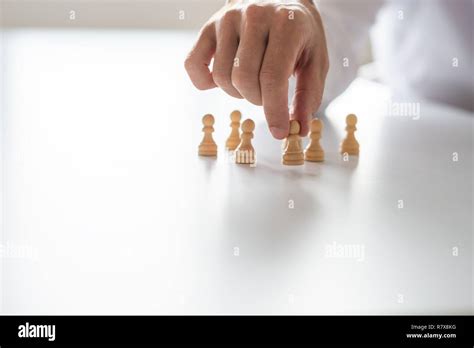 Closeup Of Businessman Hand Arranging Peasant Chess Pieces On White