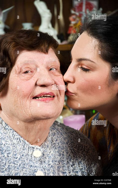 Granddaughter Kissing Her Grandma On Cheek And Looking Surprised Stock