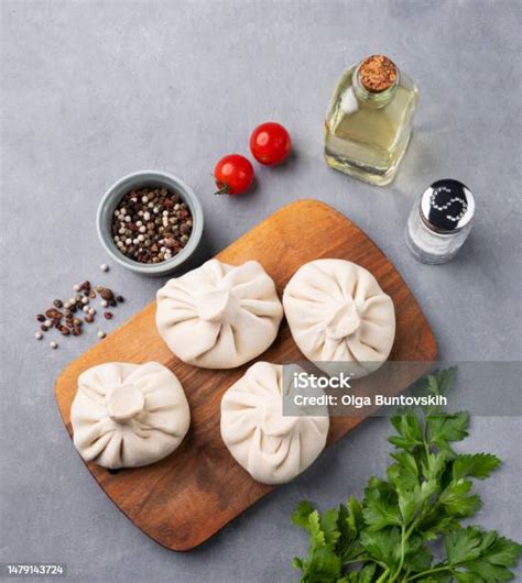 파란색 배경에 요리되지 않은 나무 판에 고기 허브 및 향신료를 곁들인 그루지야 어 Khinkali 만두 힌칼리에 대한 스톡 사진