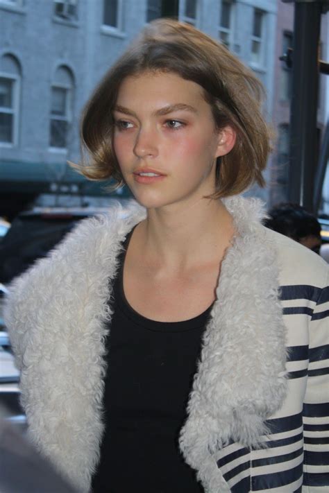 A Woman With Short Hair Wearing A Striped Jacket And Black Shirt Is Walking Down The Street