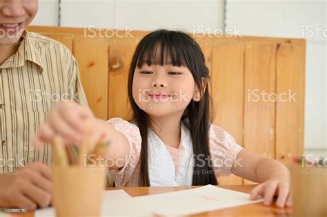 귀여운 아시아 소녀는 교실에서 미술 선생님과 함께 종이에 그림을 그리고 색칠하는 것을 즐깁니다 2명에 대한 스톡 사진 및 기타