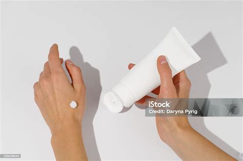 크림 질감의 한 방울을 가진 여성의 손은 흰색 고립 된 배경에 크림의 흰색 모형 튜브를 들고 있습니다 얼굴 피부 관리 미용 제품 보습 및 영양의 개념 25 29세에 대한