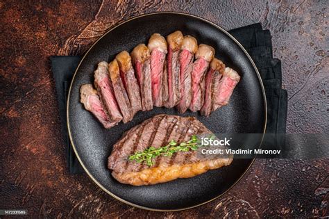 얇게 썬 구운 미디엄 레어 접시에 등심 쇠고기 스테이크를 얹습니다 어두운 배경 상위 뷰 요리하기 식품 상태에 대한 스톡 사진 및