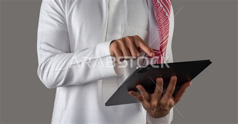 بورتريه لرجل عربي خليجي سعودي يرتدي الزي التقليدي ، يحمل بيده جهاز