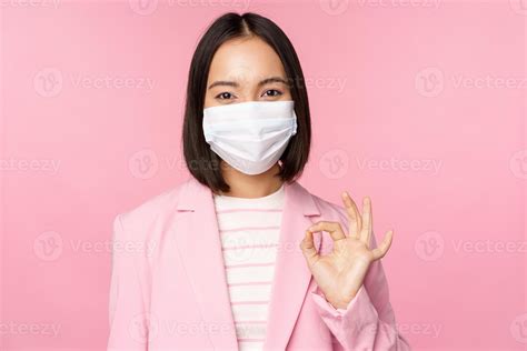 Portrait Of Asian Businesswoman In Medical Face Mask Showing Okay Sign