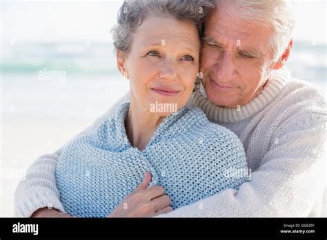 Active Senior Man Embracing His Wife From Behind On The Beach Stock