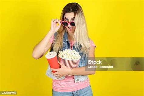 노란색 배경에 팝콘과 종이컵이 든 양동이를 들고 선글라스를 낀 젊은 여자 20 24세에 대한 스톡 사진 및 기타 이미지 20 24세 건강한 생활방식 건강한 식생활