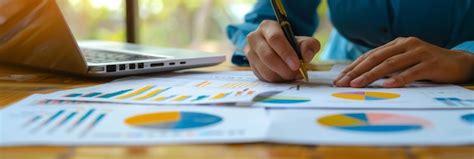 A Business Analyst Reviewing Data Charts And Graphs On A Laptop