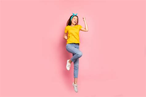 분홍색 배경을 통해 고립 된 노란색 티셔츠를 입고 비명을 지르는 주먹을 들고 흥분 한 십대의 전체 길이 사진 T 셔츠에 대한