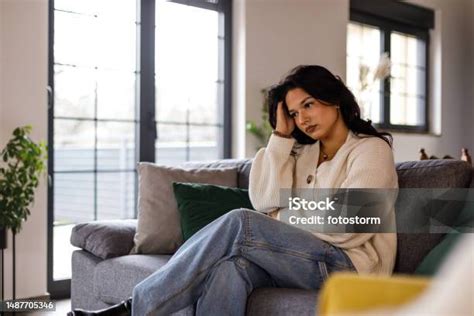 Wanita Muda Yang Khawatir Duduk Di Sofa Kepala Di Tangan Merenung Foto