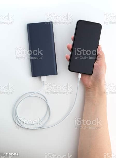 전원 은행과 스마트 폰은 흰색 바탕에 손에 스마트폰이 전원 은행에서 충전 중입니다 Usb 케이블에 대한 스톡 사진 및 기타