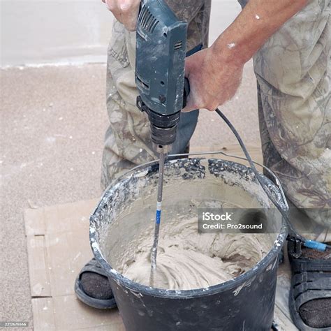 A Worker Stirs The Construction Mixture Plaster In A Bucket With An