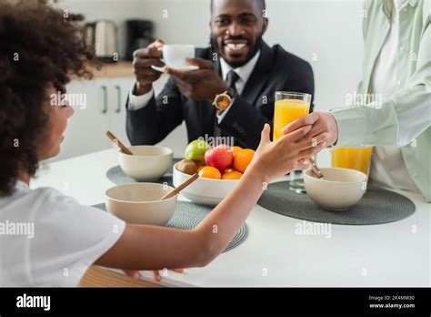 African American Woman Giving Glass Of Orange Juice To Happy Daughter