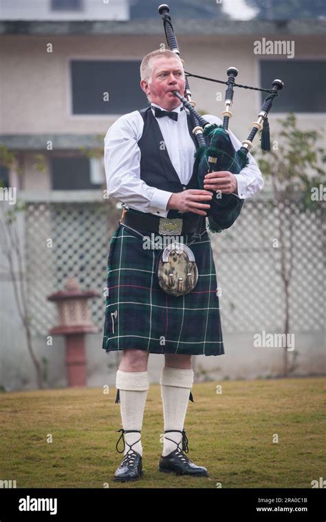 Scottish Piper From Scotland In Traditional Outfit With Tartan Kilt