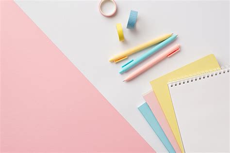 학교 용품 개념 카피 스페이스가있는 이중 색상의 흰색과 분홍색 배경에 다채로운 카피북 펜과 접착 테이프의 문구 더미의 상단보기