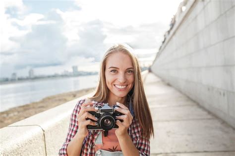 Premium Photo Smiling Young Woman With A Camera At The Riverside