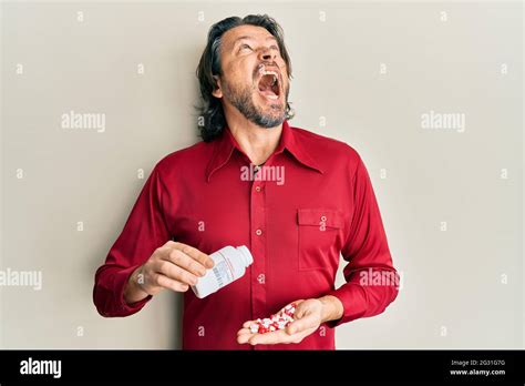 Middle Age Handsome Man Taking Pills Angry And Mad Screaming Frustrated