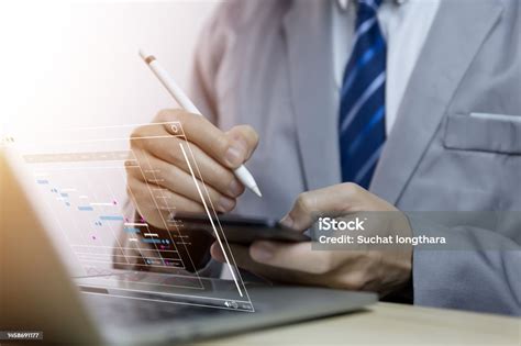 노트북과 스마트폰을 사용하는 남성 관리자 사무실에서 사업 계획 프로젝트 일정을 관리하고 가상 화면에 Gantt 차트를 표시합니다